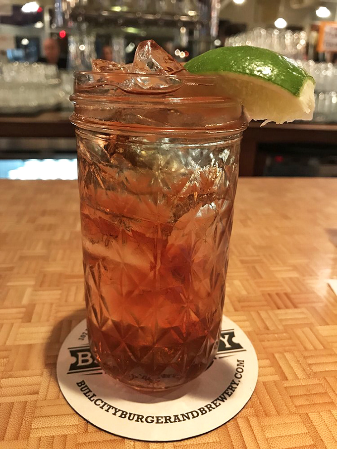 This isn't just a cocktail&mdash;it's liquid craftsmanship in a mason jar, garnished with lime and served on a coaster that reminds you exactly where this magic happened.
