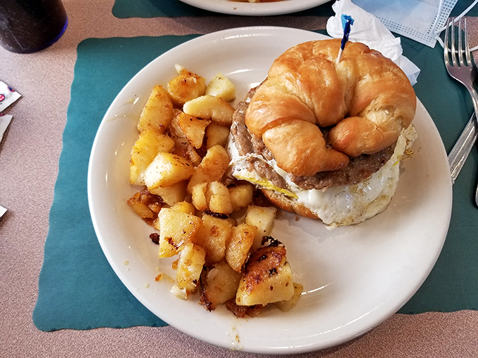Breakfast gets the royal treatment when a buttery croissant becomes the throne for a perfectly cooked burger and egg&mdash;with home fries as loyal subjects.