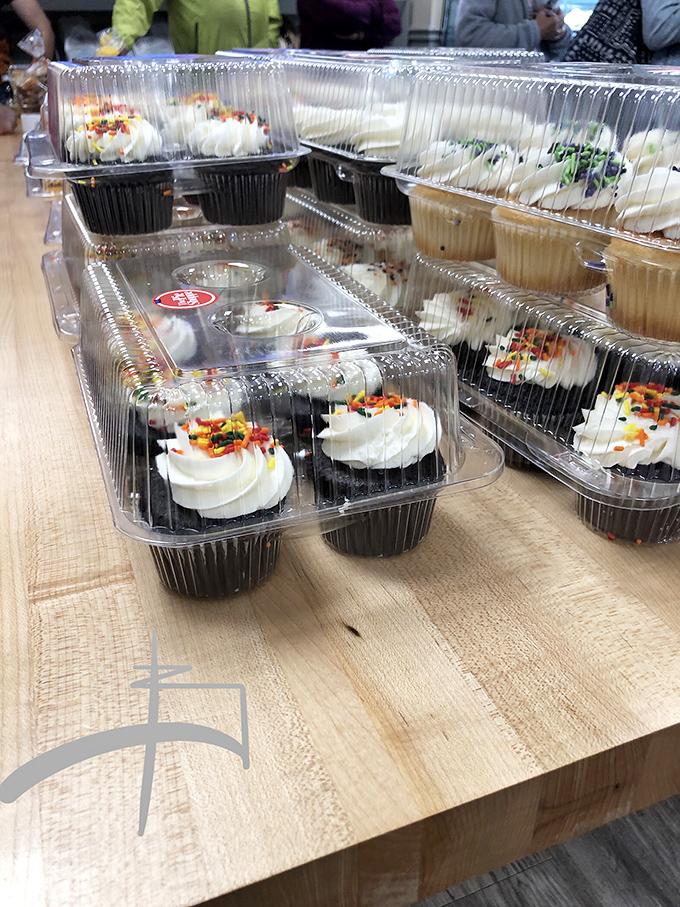 Cupcakes nestled in their plastic homes, frosting swirled high like edible architecture, waiting to transform an ordinary day into a celebration.