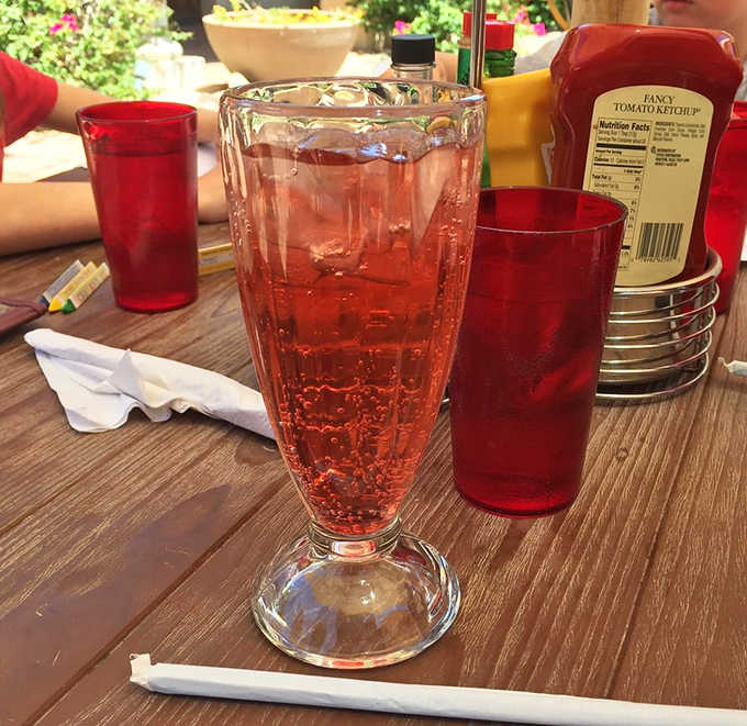 That ruby-red soda in a classic fountain glass isn't just a drink—it's liquid nostalgia served with a side of Arizona sunshine.