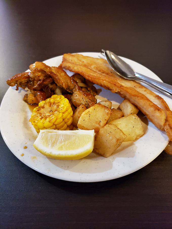 A seafood sampler that hits all the right notes—crispy fish, golden potatoes, sweet corn, and that lemon wedge standing by like a faithful sidekick.