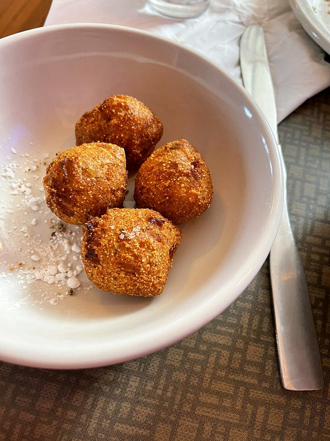 Hush puppies dusted with powdered sugar sit like golden orbs of cornmeal perfection, waiting to silence hunger with Southern-inspired charm.