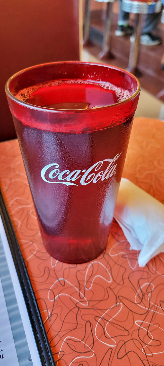 That classic Coca-Cola glass isn't just a vessel; it's a time machine. Cold, refreshing, and absolutely mandatory with diner fare.