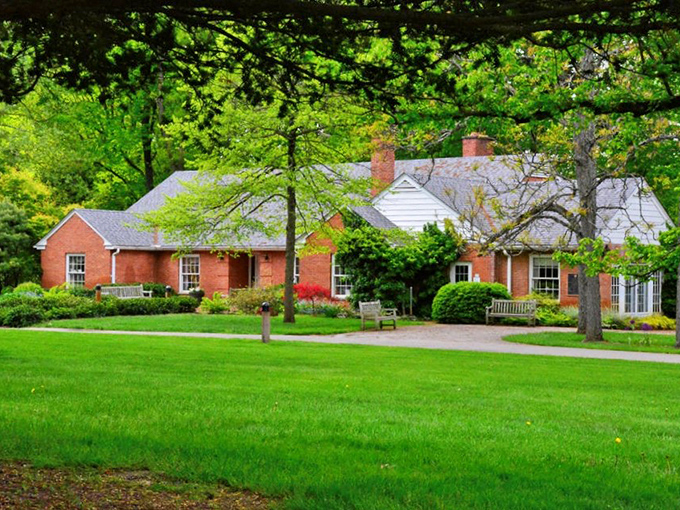 The stately Innis House welcomes visitors with classic brick charm. Spring flowering trees frame this historic home like nature's own picture frame.