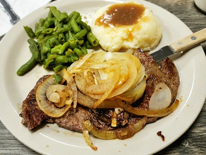 Tender steak topped with caramelized onions alongside perfectly cooked vegetables &ndash; proof that simple ingredients prepared well need no fancy embellishment.