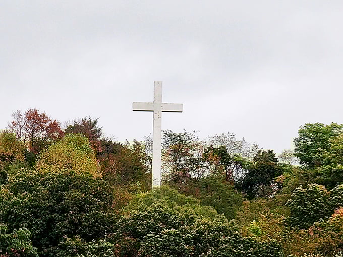 Rising above the autumn foliage, this cross stands as a silent landmark for train passengers, marking the journey through Ohio's spiritual landscape.