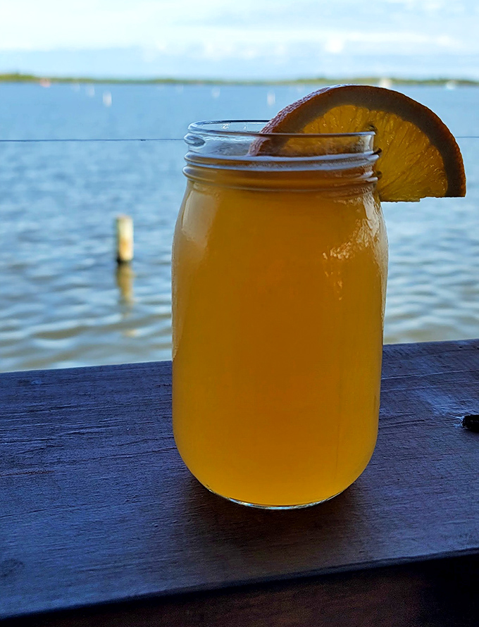 That mason jar isn't just holding orange juice—it's framing the spectacular lagoon view that makes every sip taste like liquid sunshine.
