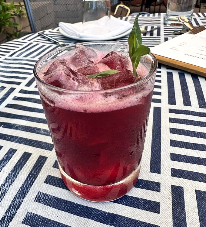 This ruby-red cocktail, garnished with fresh herbs, isn't just a drink&mdash;it's liquid courage before your meat adventure begins.