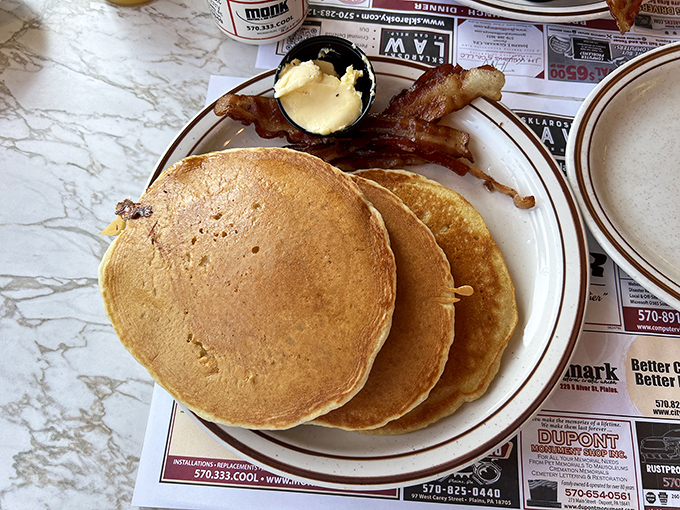 Stack of pancakes so perfectly golden, they practically glow with breakfast righteousness and maple syrup dreams.