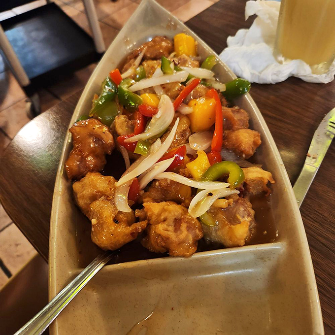 A boat-shaped vessel delivering tropical cargo&mdash;crispy pork with colorful peppers and onions that would make even a luau master nod in approval.