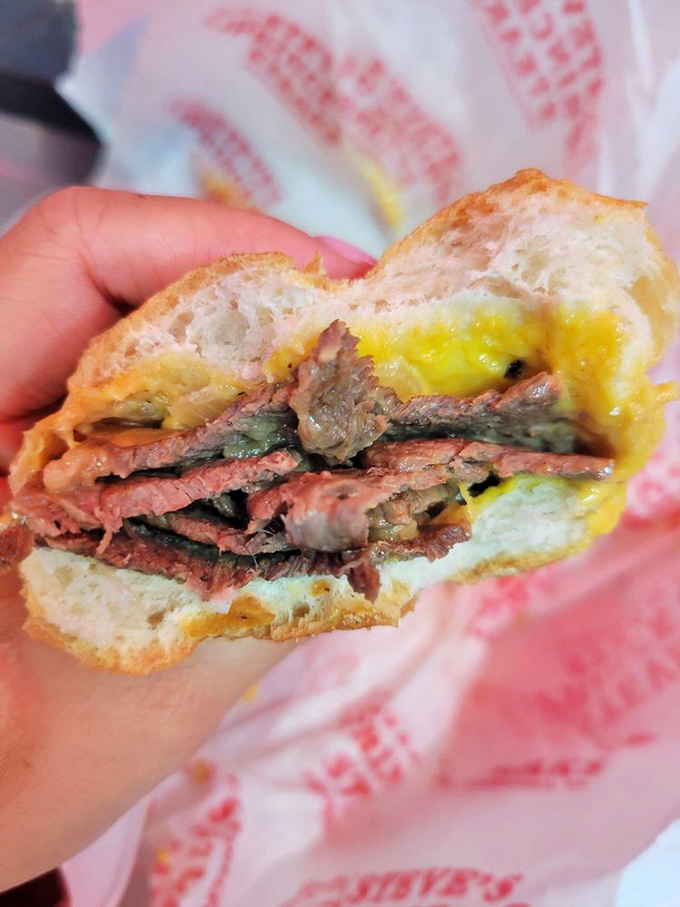 The Whiz-enhanced cheesesteak in its natural habitat—that distinctive yellow cascade isn't just cheese, it's liquid sunshine on beef.