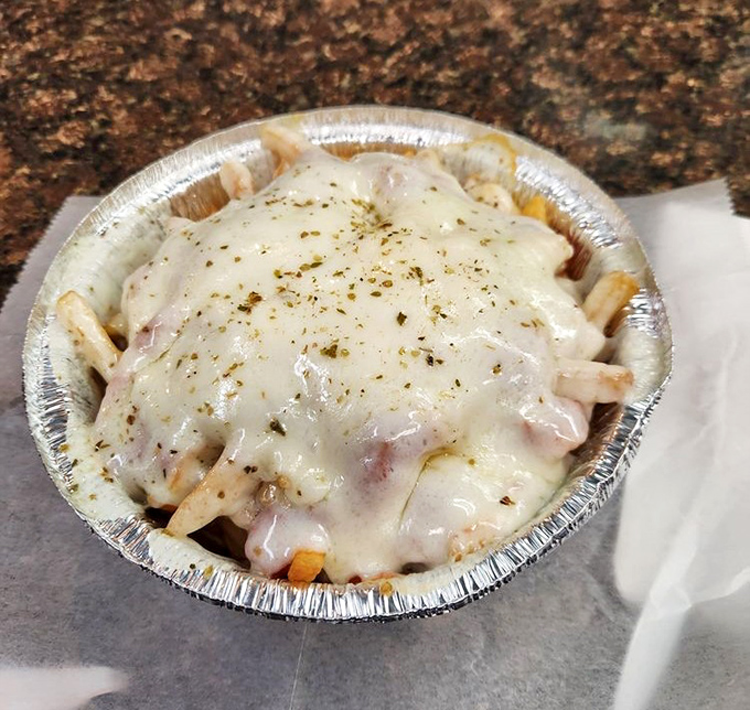 Cheese-smothered fries in their natural aluminum habitat. Like nachos that went to college in Pennsylvania and came back transformed.