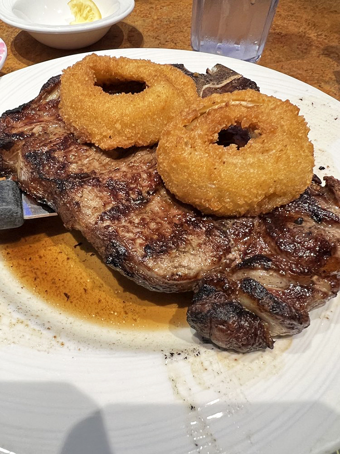 This porterhouse steak isn't just dinner; it's a primal experience with onion rings perched on top like delicious, crispy halos.