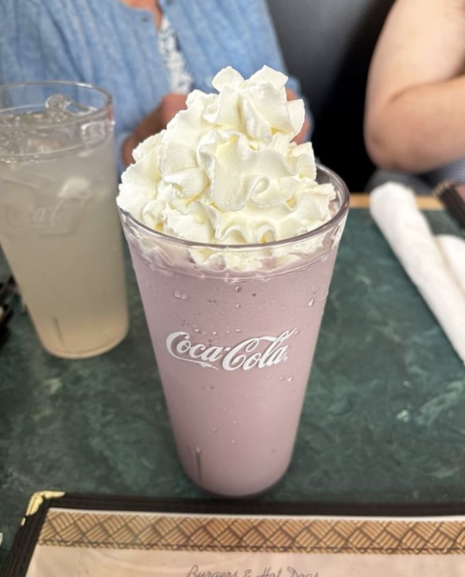 A raspberry milkshake topped with a cloud of whipped cream. Dessert? Beverage? Both? The debate ends when the straw hits your lips.