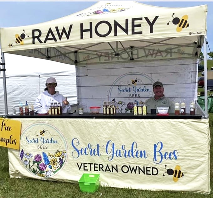 Local honey vendors offering liquid gold samples, their bee-themed display as sweet as the products they're proudly selling.