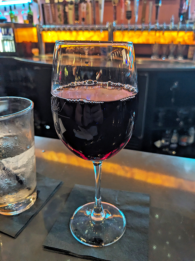 A glass of robust red wine waiting patiently at the bar &ndash; because every great meal deserves an equally distinguished liquid companion.