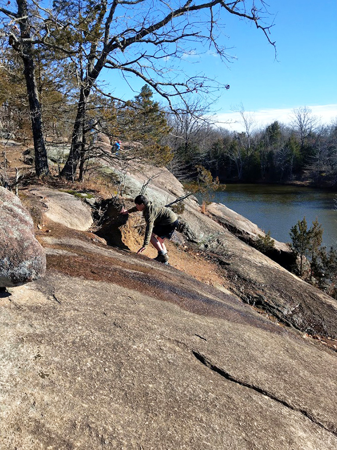 Winter reveals a different side of Elephant Rocks, where a visitor explores the stark beauty of ancient stone against the backdrop of a quiet pond.