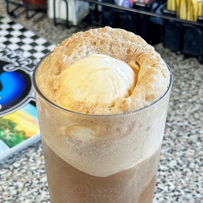 The root beer float rises majestically from its glass like a caffeinated cloud, promising sweet, fizzy nostalgia with every sip.