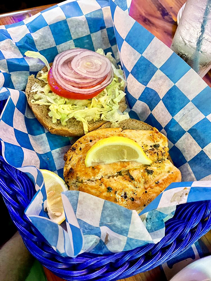 A perfectly grilled fish sandwich served in a blue-checkered basket – the kind of honest, unfussy meal that makes vacation memories last.