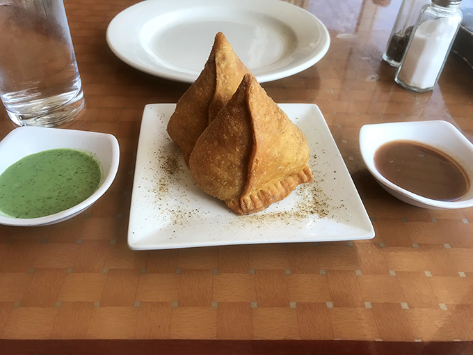 Samosas: the triangular treasures of the appetizer world, perfectly fried and flanked by vibrant chutneys that add both color and kick.