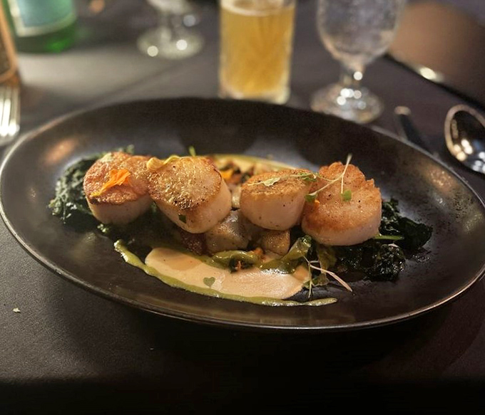 Perfectly seared scallops perched atop vibrant greens&mdash;ocean treasures that have found their rightful throne on this sophisticated plate.