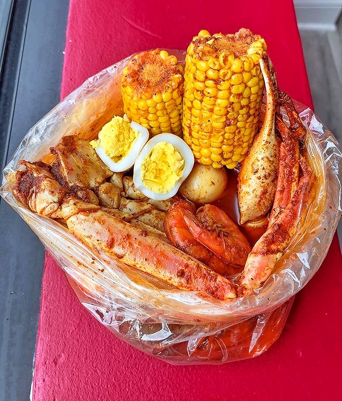 The seafood boil arrives like a treasure chest&mdash;crab legs, corn, potatoes, and eggs swimming in seasoned glory, all sealed in plastic for maximum flavor infusion.
