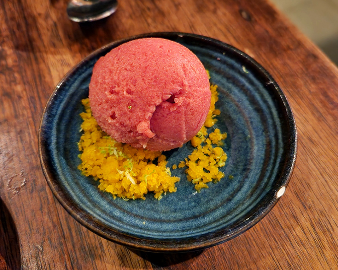 A vibrant scoop of sorbet resting on sunshine-colored crumble&mdash;summer captured in a bowl, waiting to refresh your palate.