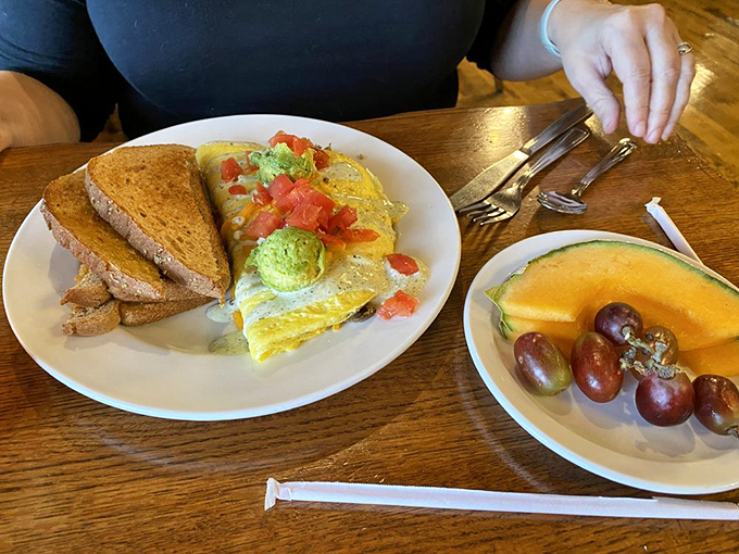 Breakfast architecture at its finest &ndash; an omelet stuffed with avocado and topped with fresh tomatoes, with fruit providing a sweet counterpoint.