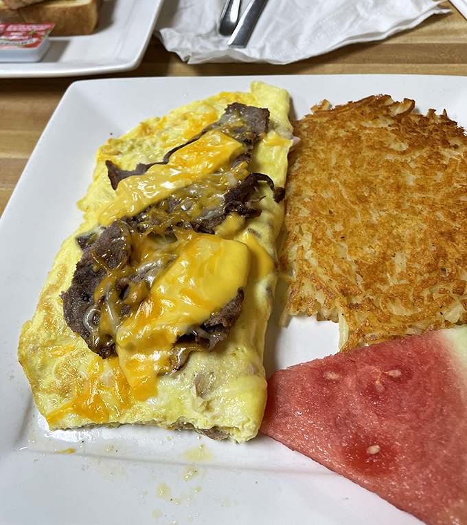 Mushroom omelet magic unfolds with melted cheese cascading like edible sunshine across perfectly cooked eggs and toast.