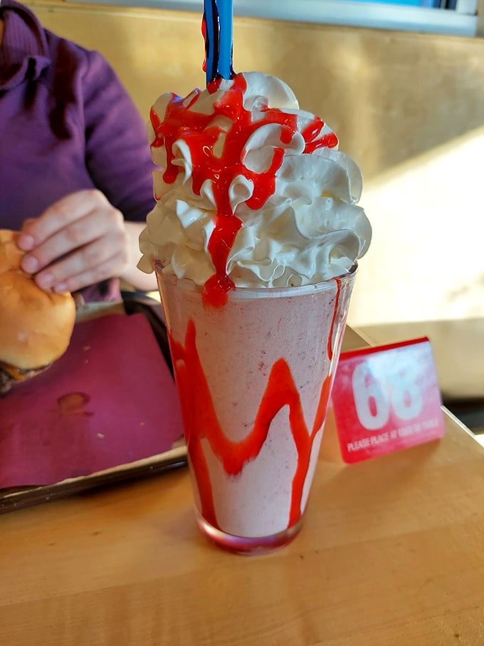 This strawberry milkshake with its dramatic red drizzle isn't just a drink—it's dessert with theatrical flair. Whipped cream mountain included.