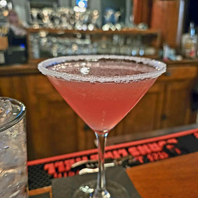 That vibrant pink martini isn't just a drink, it's a conversation piece with a sugar rim that's dressed better than most people at the party.