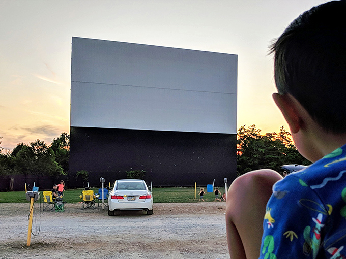 The cathedral of outdoor cinema stands silent at dusk, patiently waiting to illuminate imaginations and unite strangers.