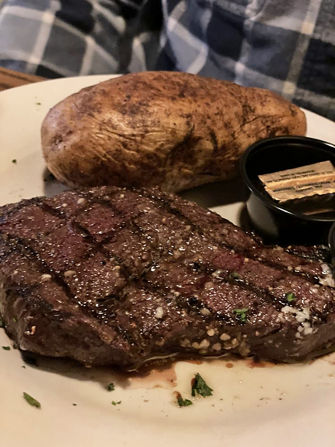 A steak with the kind of char that makes vegetarians temporarily question their life choices, paired with a baked potato awaiting its butter destiny.