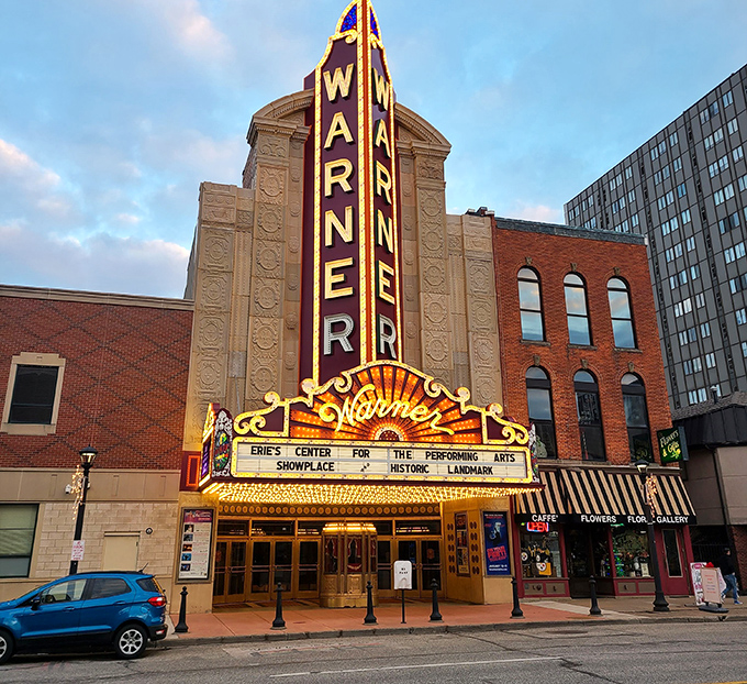 The Warner Theatre's marquee glows like a beacon of culture in Erie's evening landscape, a gilded reminder of entertainment's golden age.