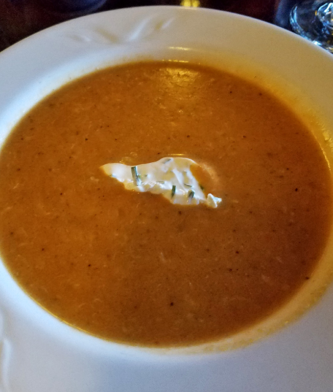 A bisque so velvety it could moonlight as a spa treatment. That single piece of crab is like finding treasure in an amber sea.