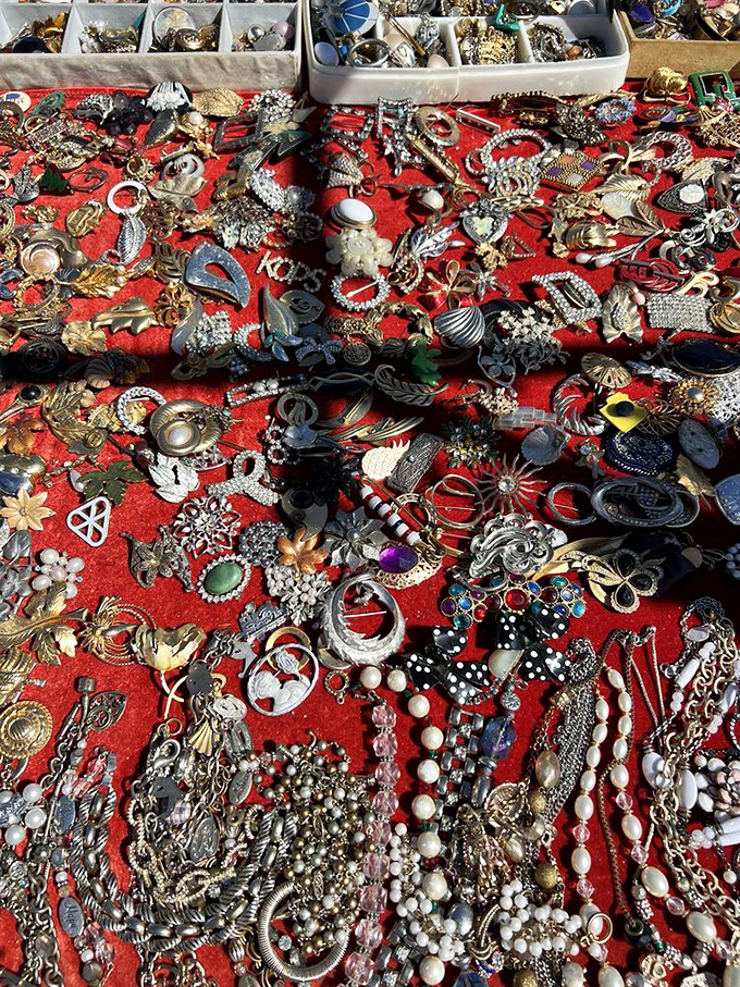 Treasure island on red velvet. Vintage jewelry sprawls like a pirate's bounty&mdash;each piece waiting to become someone's "where did you get that?" conversation starter.