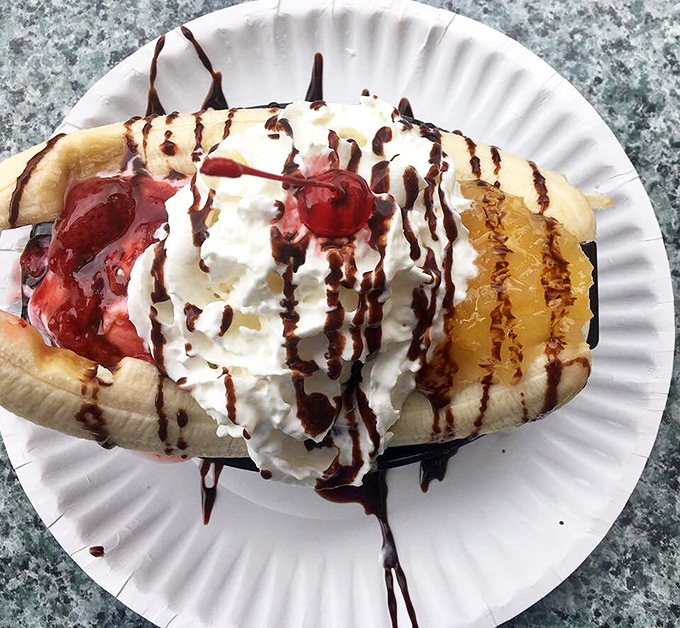 Banana split heaven! This isn't dessert, it's a childhood memory served on a paper plate with chocolate drizzle calligraphy.