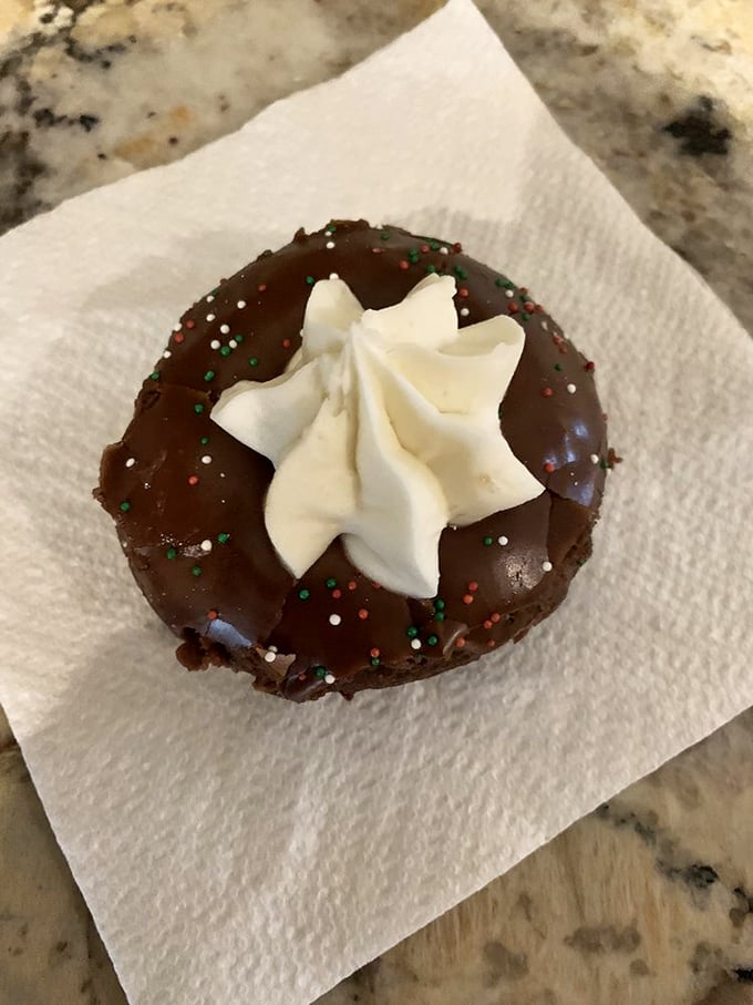 A chocolate donut wearing its holiday best &ndash; festive sprinkles and a cream star that's dressed for the occasion.