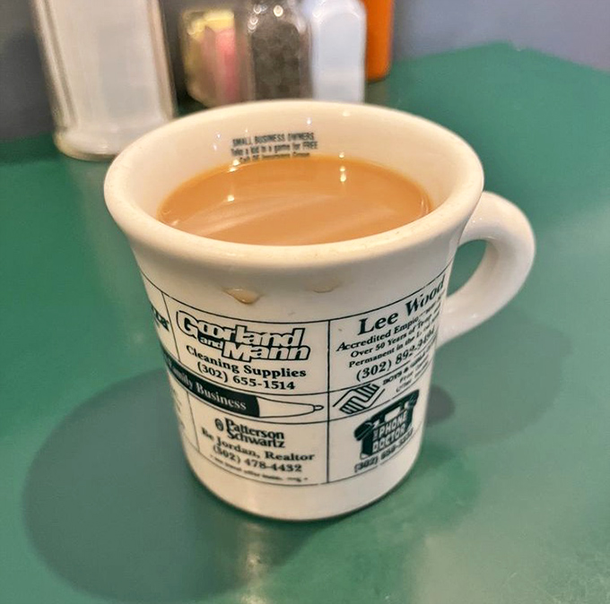 Coffee served in a mug advertising local businesses &ndash; because in a proper diner, even your caffeine supports the community.