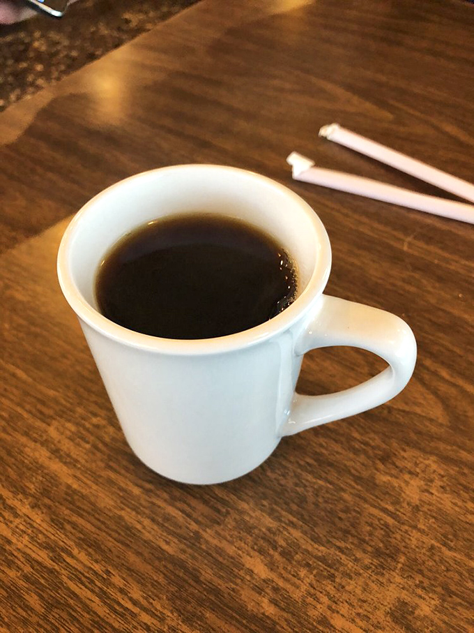 That humble white mug holds liquid persistence&mdash;the kind of honest, robust coffee that doesn't need fancy names or elaborate preparation to get you through your day.