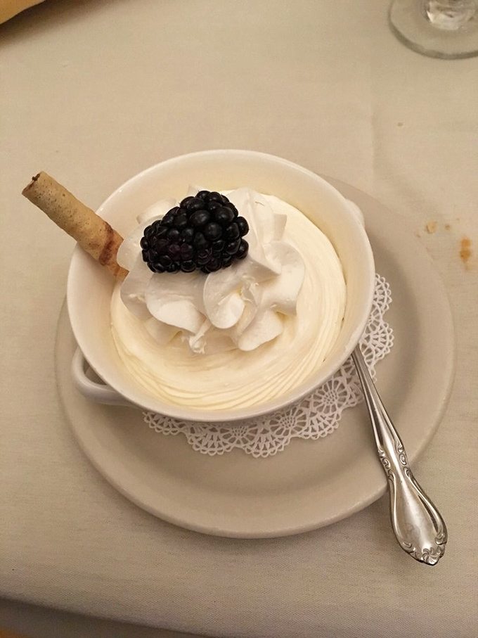 Dessert that whispers "sophistication" while screaming "indulgence" – a cloud of cream topped with a single perfect blackberry and a cookie garnish.