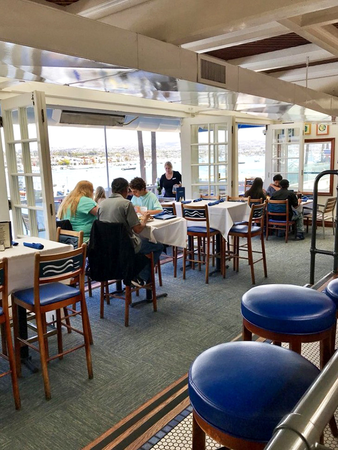 The dining room buzzes with conversation as patrons enjoy the ultimate dinner theater &ndash; Newport Harbor's constant parade of boats and seabirds.
