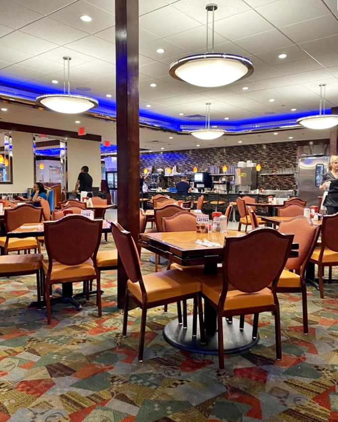 The dining room hums with possibility, each table a stage where breakfast dreams come true under the watchful glow of blue accent lighting.