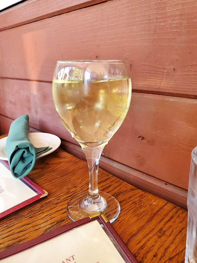 A glass of chilled white wine against rustic wood paneling&mdash;like finding civilization in the wilderness. The perfect companion for seafood adventures.