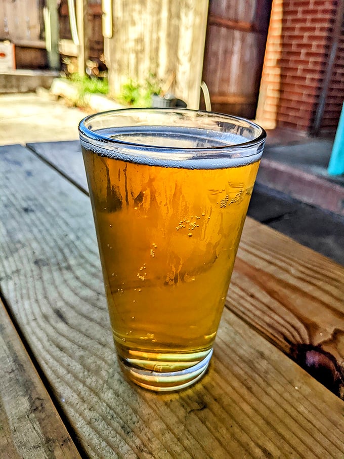 A cold beer on a wooden table outside Ray Ray's—because sometimes the perfect barbecue wingman doesn't say a word.