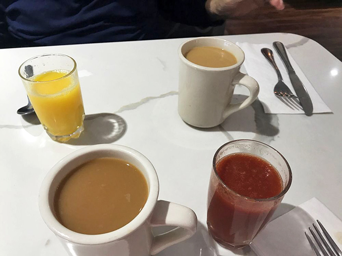 Morning beverages lined up like old friends: orange juice bringing sunshine, coffee offering wisdom, and water standing by for moral support.