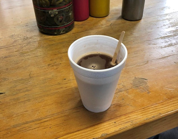 A humble styrofoam cup of cocoa sits atop worn wood - proof that Bill's understands sometimes you need something besides soda with your burger.