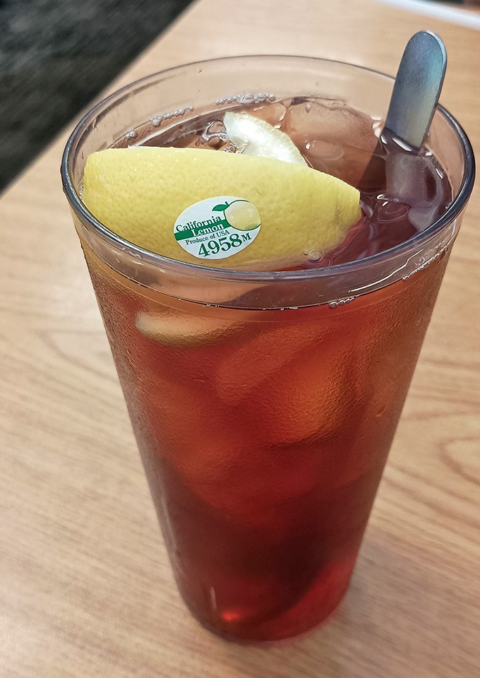Even the iced tea gets the royal treatment—perfectly brewed, properly chilled, and served with a lemon slice wearing its produce sticker like a tiny badge of honor.