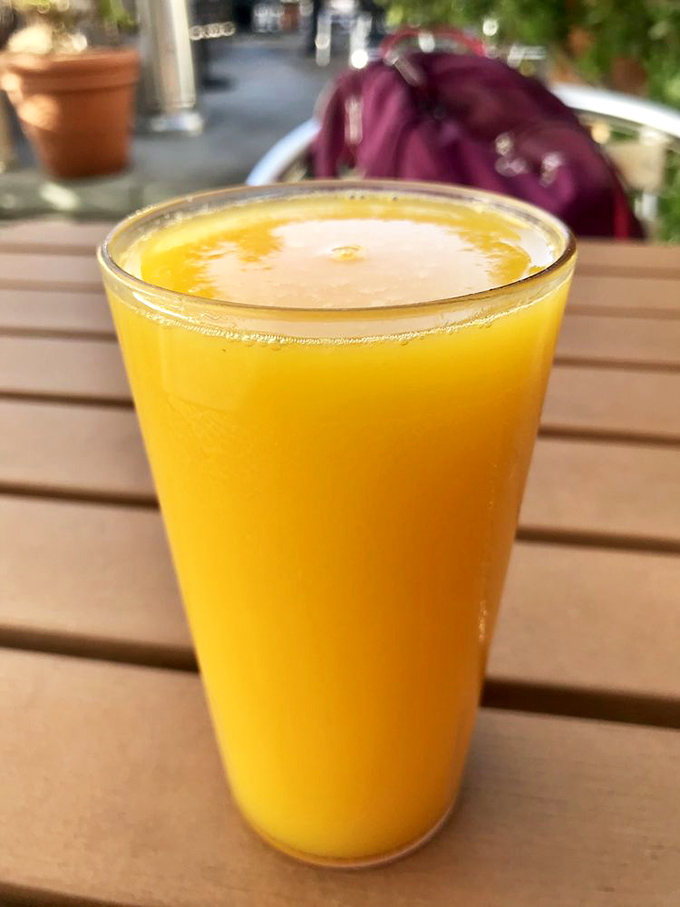 Fresh orange juice catches the morning light like liquid sunshine, the perfect bright companion to hearty breakfast fare.