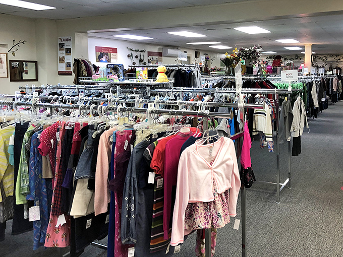 The women's clothing area stretches into the distance like a textile rainbow, each garment holding the possibility of becoming someone's "Can you believe I thrifted this?" triumph.